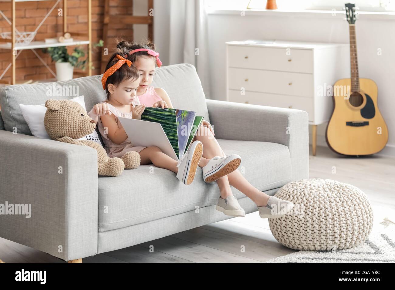 Cute little sisters reading book at home Stock Photo - Alamy