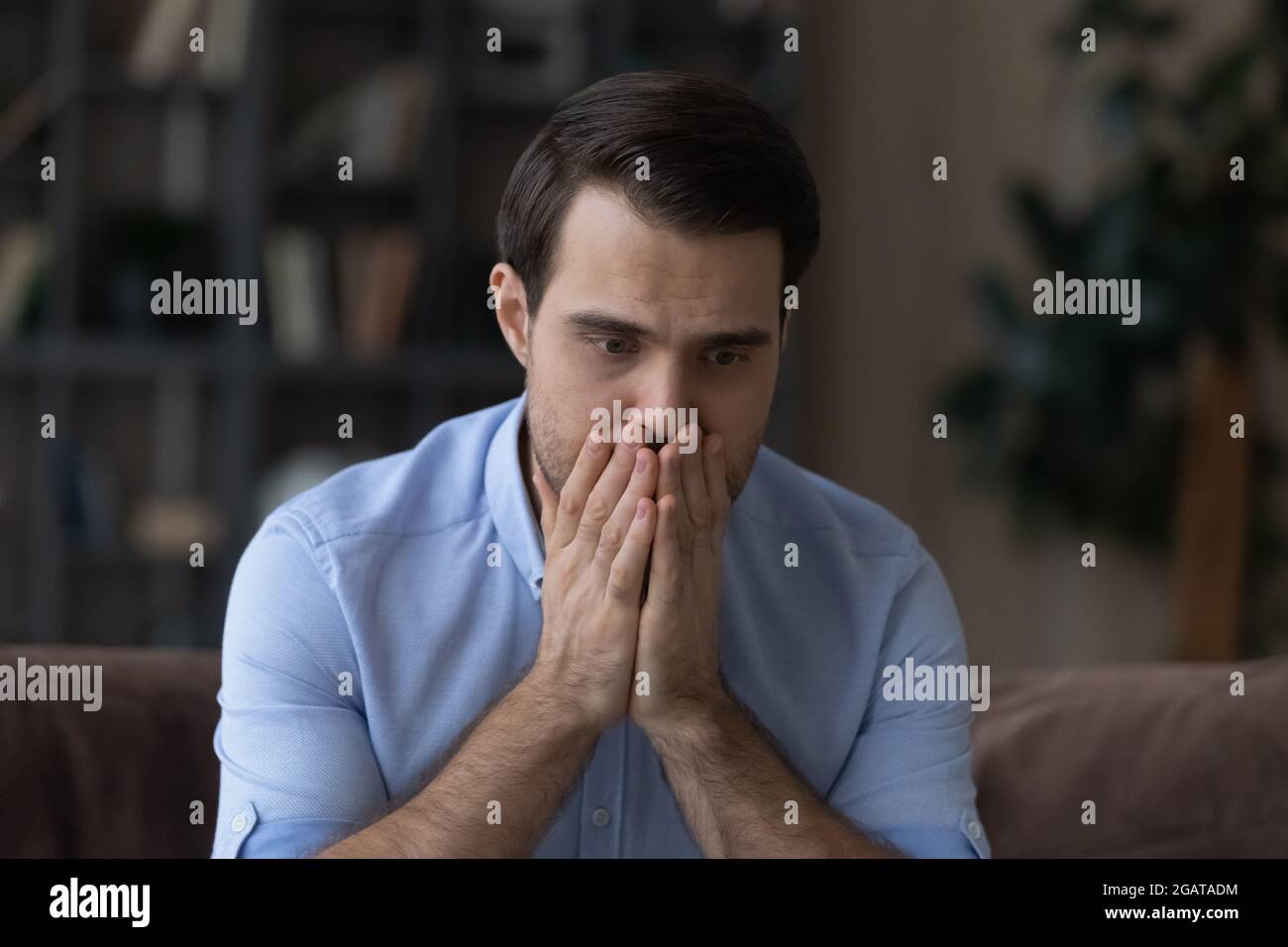 Worried nervous millennial man covering mouth with hands feeling fear ...