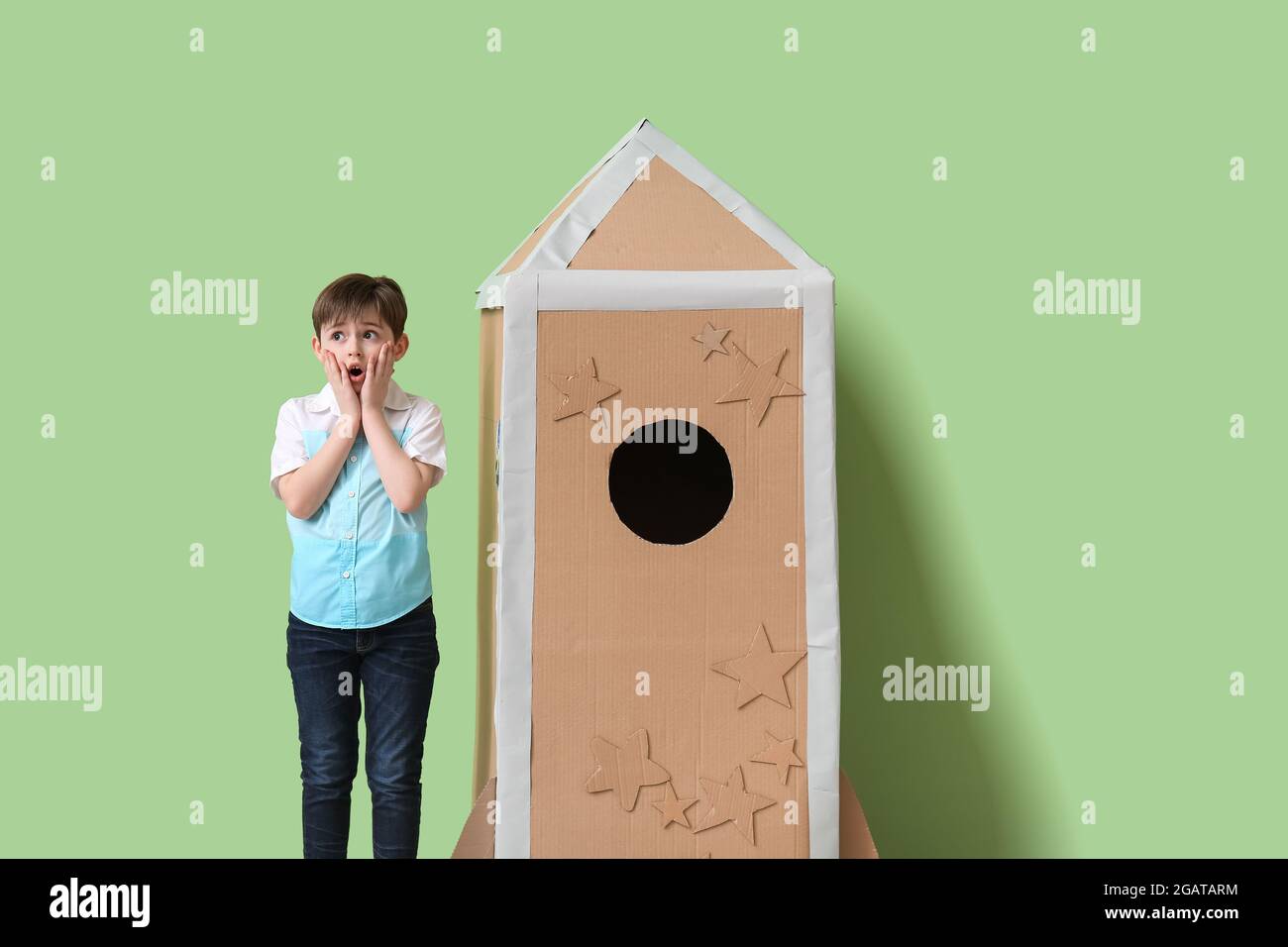 Shocked little boy with cardboard rocket on color background Stock ...