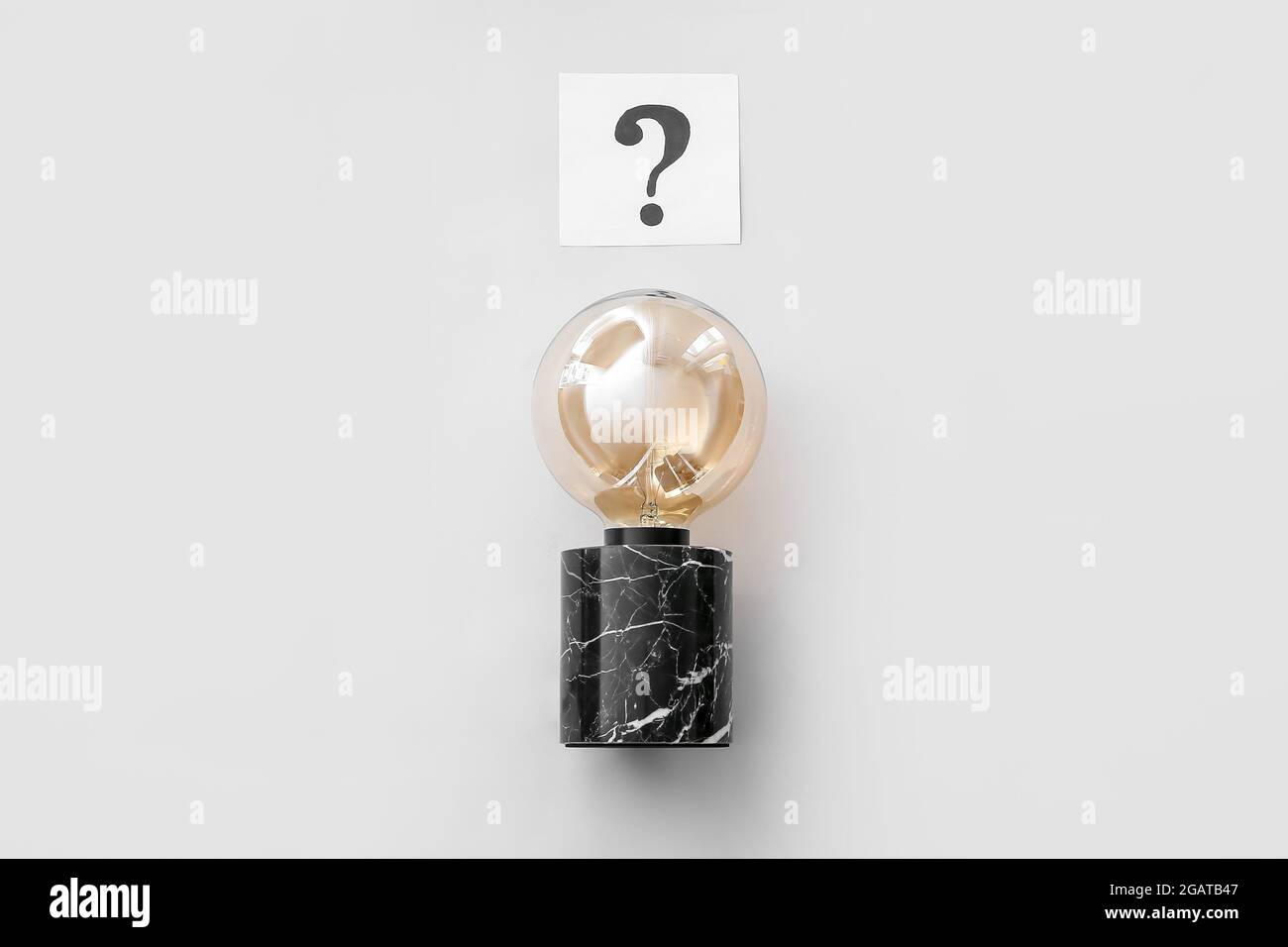 Stylish lamp and paper with question mark on light background Stock ...