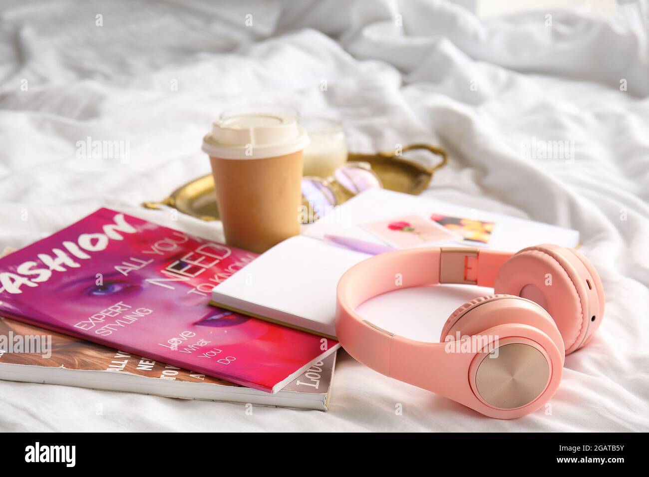 Modern headphones with magazines on bed Stock Photo - Alamy