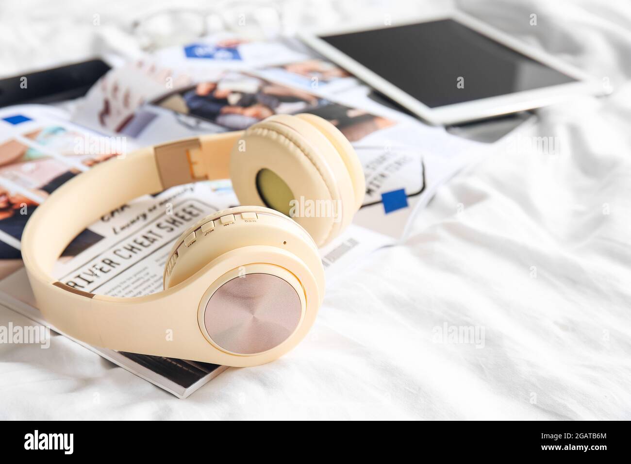 Modern headphones with magazine on bed, closeup Stock Photo - Alamy
