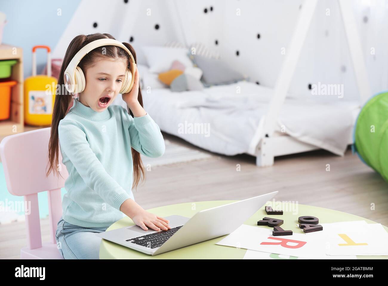 Little girl with laptop training pronounce letters at home Stock Photo ...