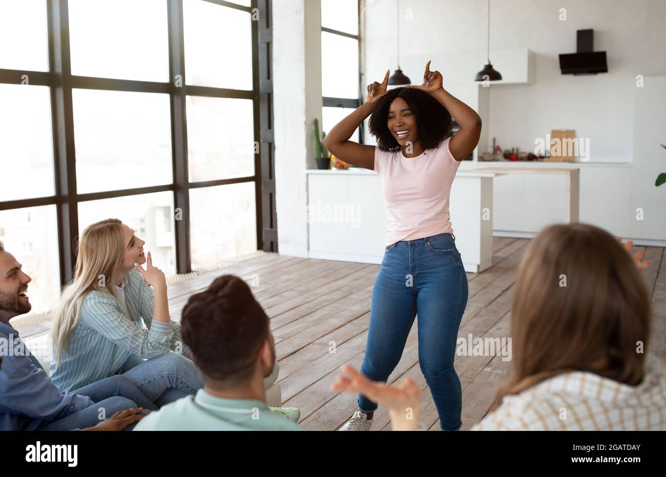 Positive diverse friends playing guess who game, showing pantomime ...