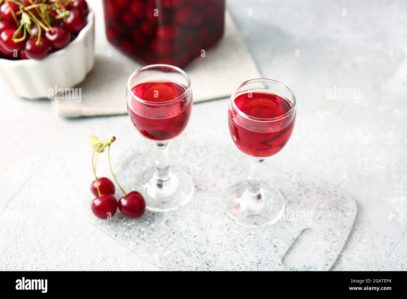 Glasses of sweet cherry wine on light background Stock Photo - Alamy