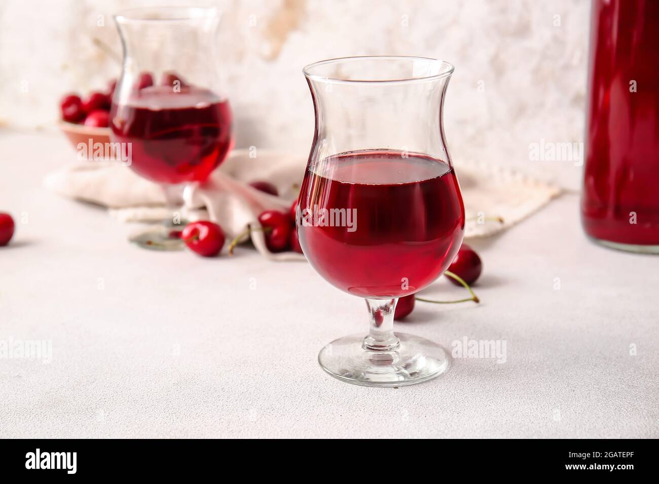 Glasses of sweet cherry wine on light background Stock Photo - Alamy