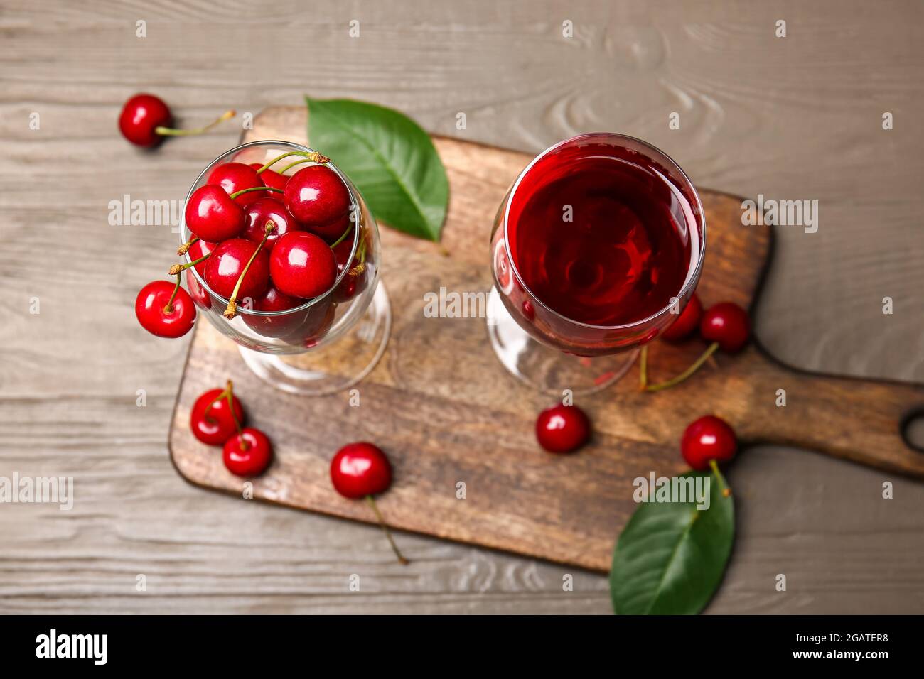 Glass of sweet cherry and wine on wooden background Stock Photo - Alamy