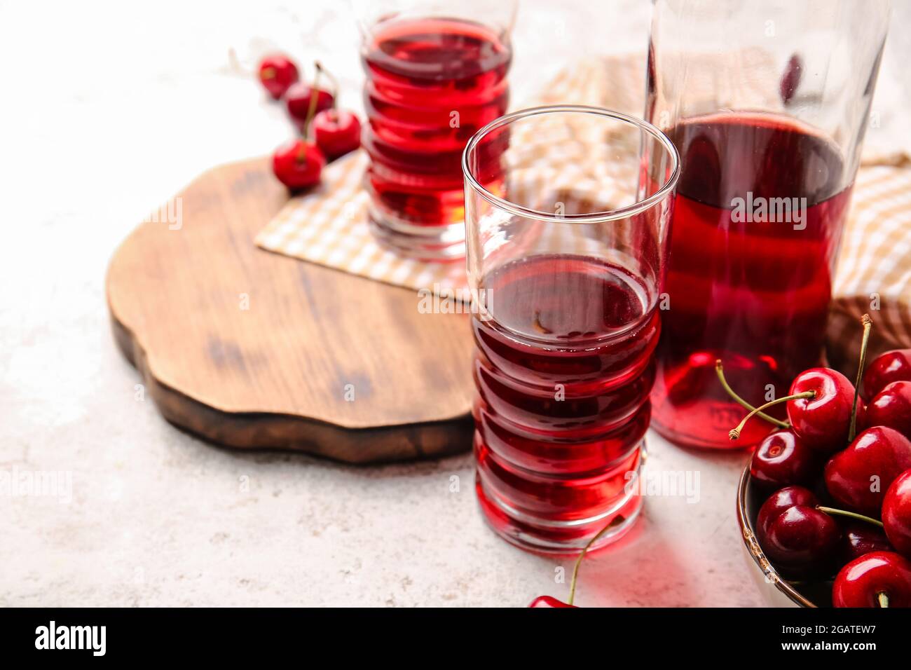 Glasses and bottle of sweet cherry wine on light background, closeup ...