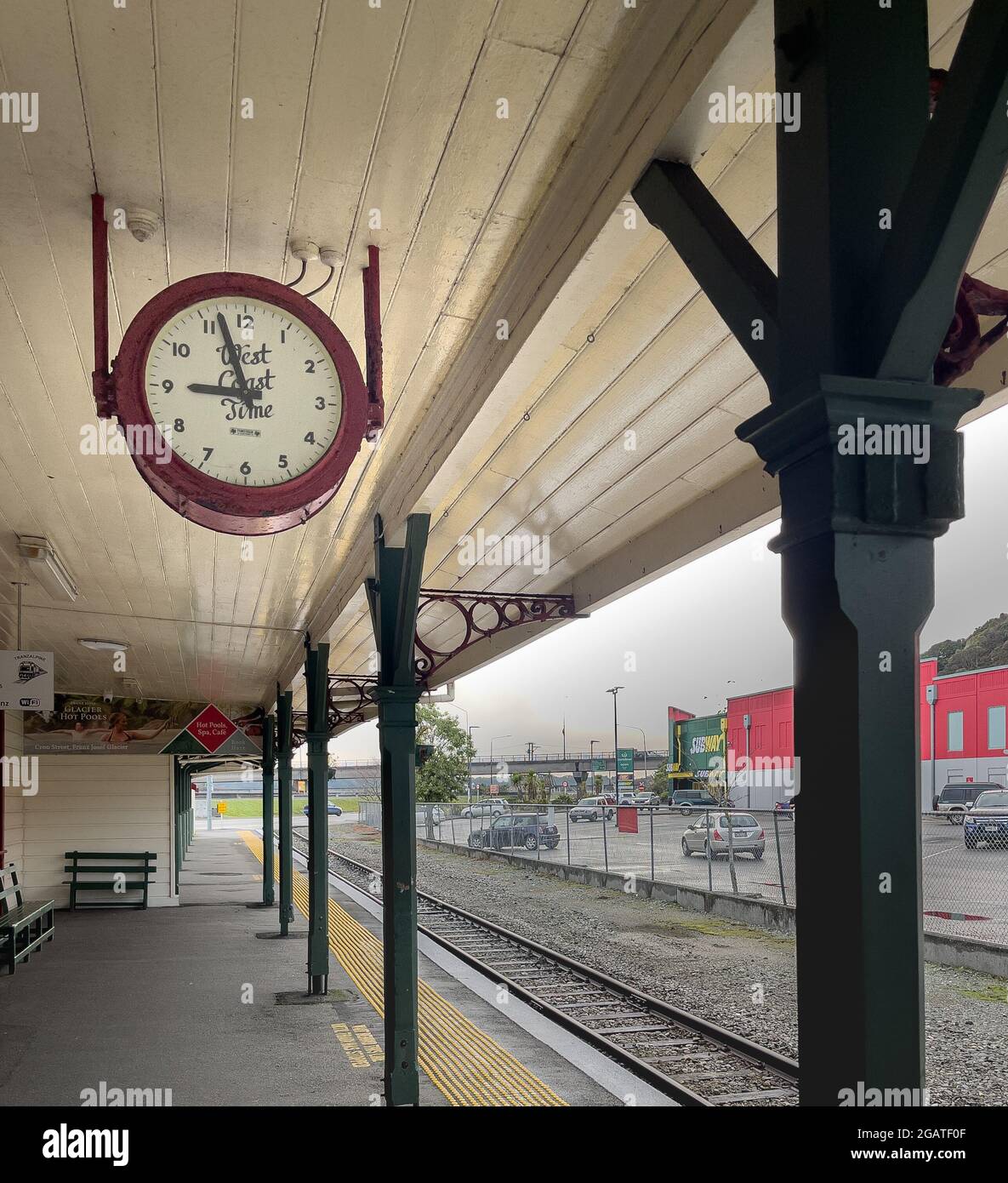 A vertical shot of a clock hanging from a ceiling of an outdoor station ...
