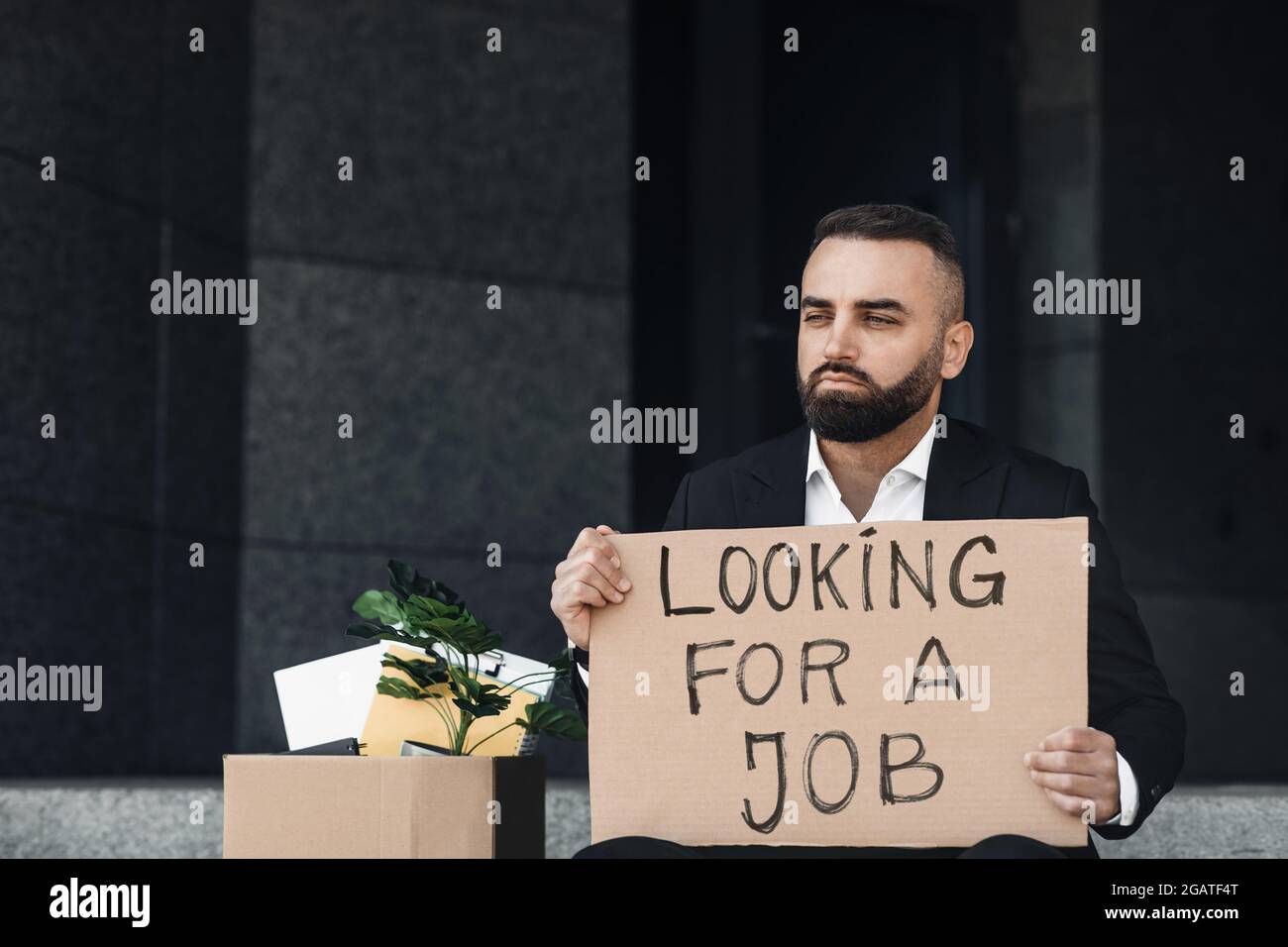 Unhappy unemployed man holding cardboard sign with Looking For a Job ...