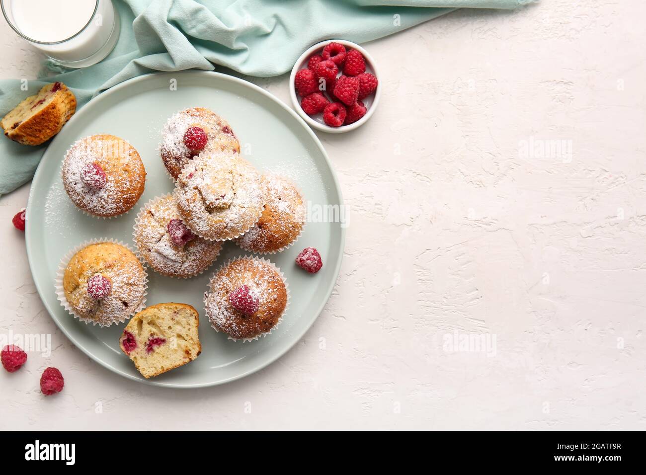 Tray with tasty raspberry muffins and glass of milk on light background ...