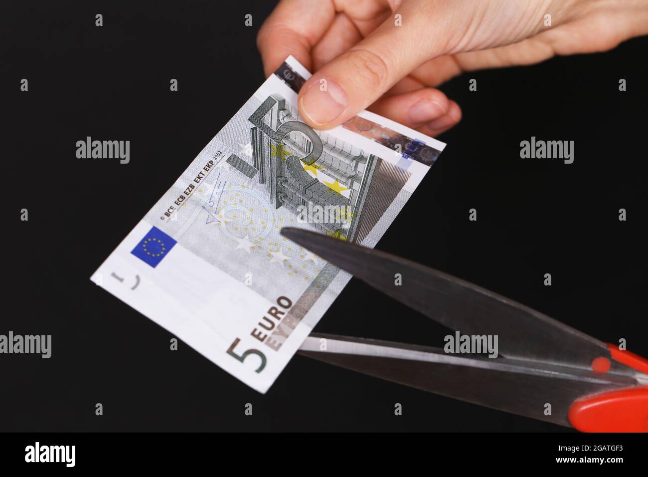 Hands with scissors cutting Euro banknote, on black background Stock ...
