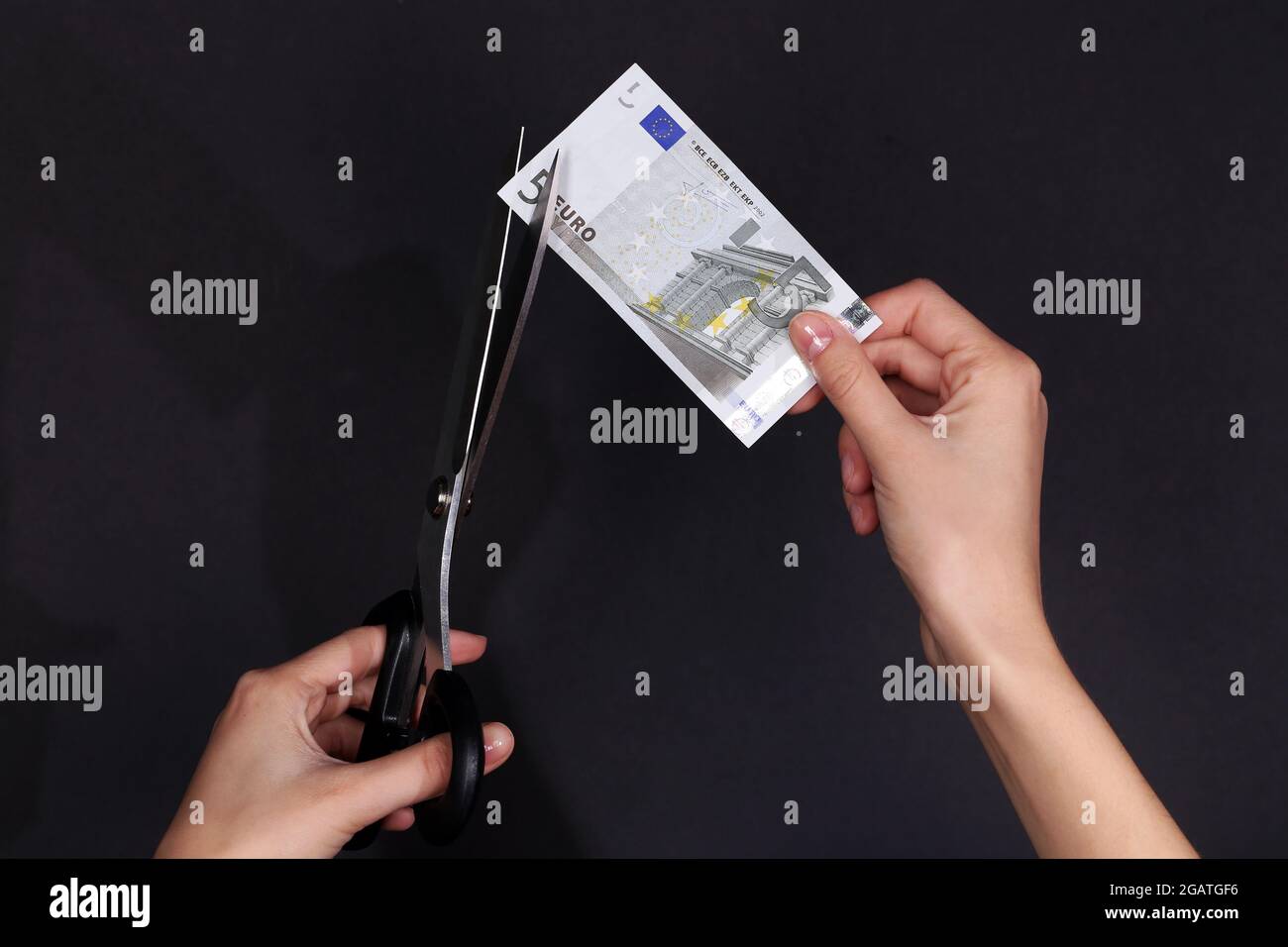 Hands with scissors cutting Euro banknote, on black background Stock ...