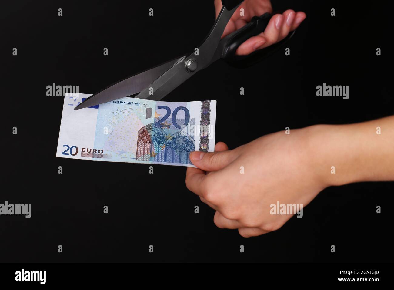 Hands with scissors cutting Euro banknote, on black background Stock ...