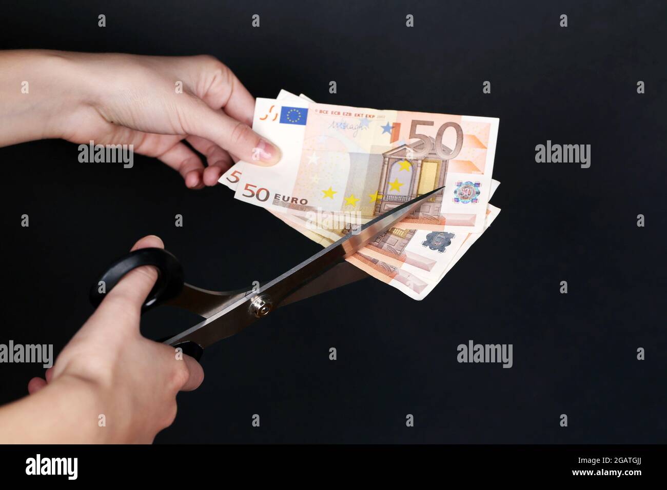 Hands with scissors cutting Euro banknotes, on black background Stock ...