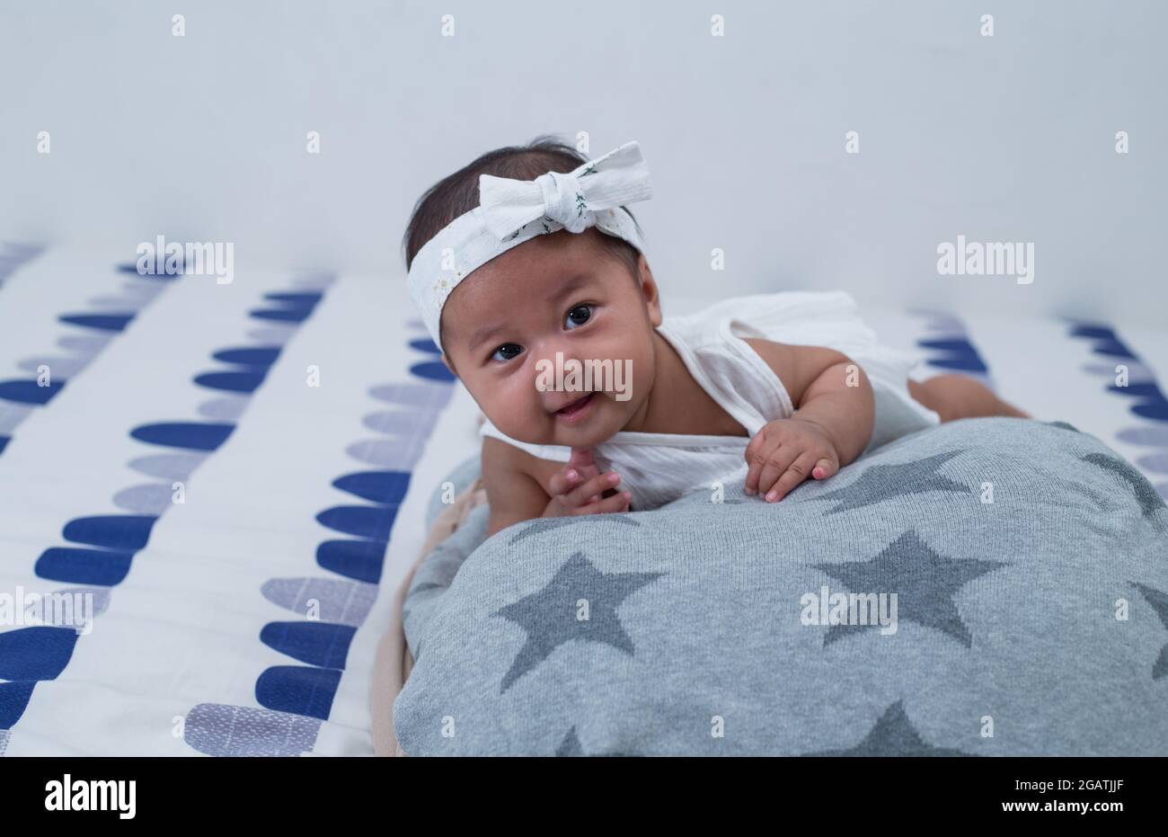 A beautiful southeast asian baby girl in a white dress and headband ...