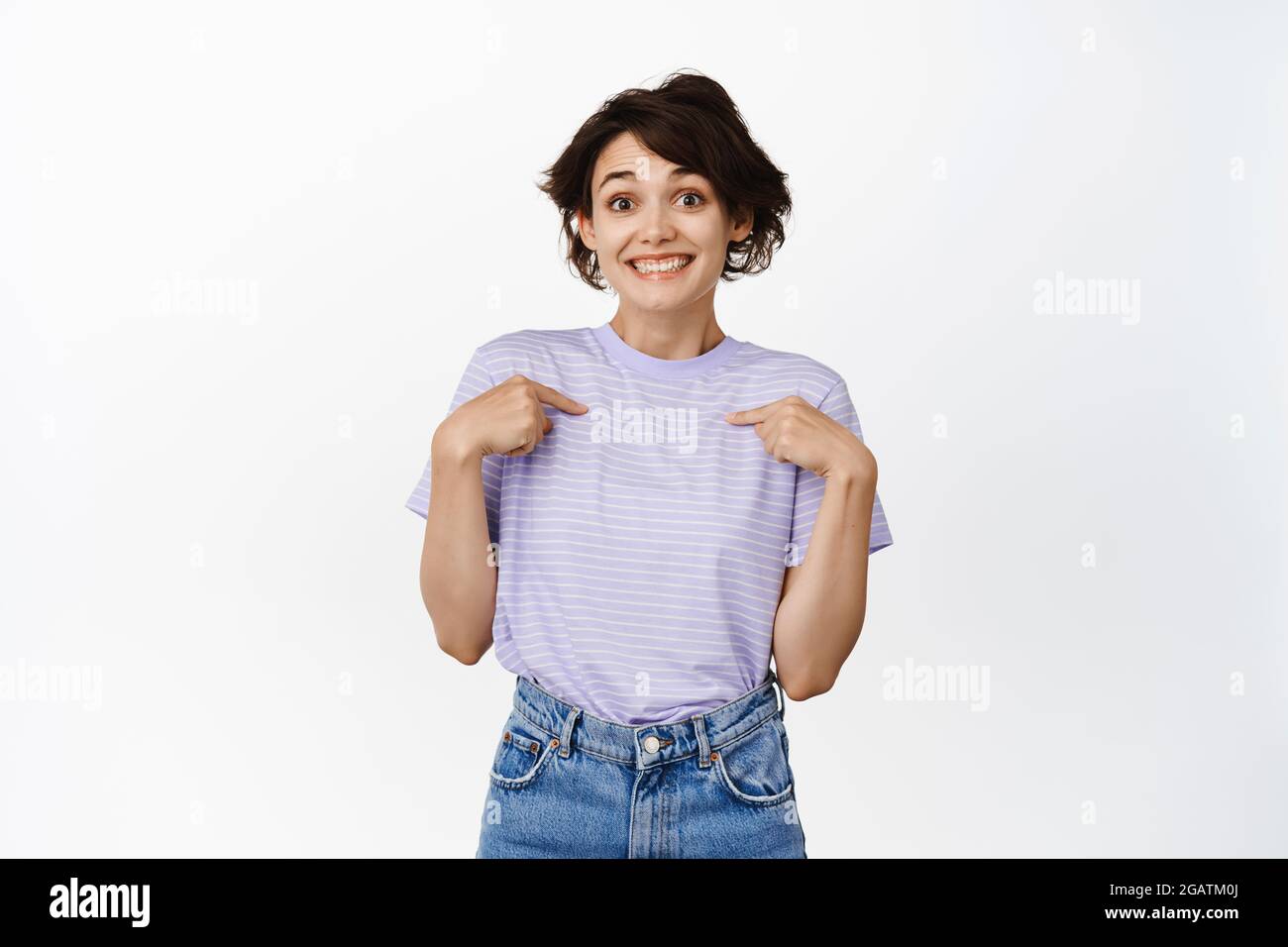 Cute brunette girl points at herself and smiles with modest face ...