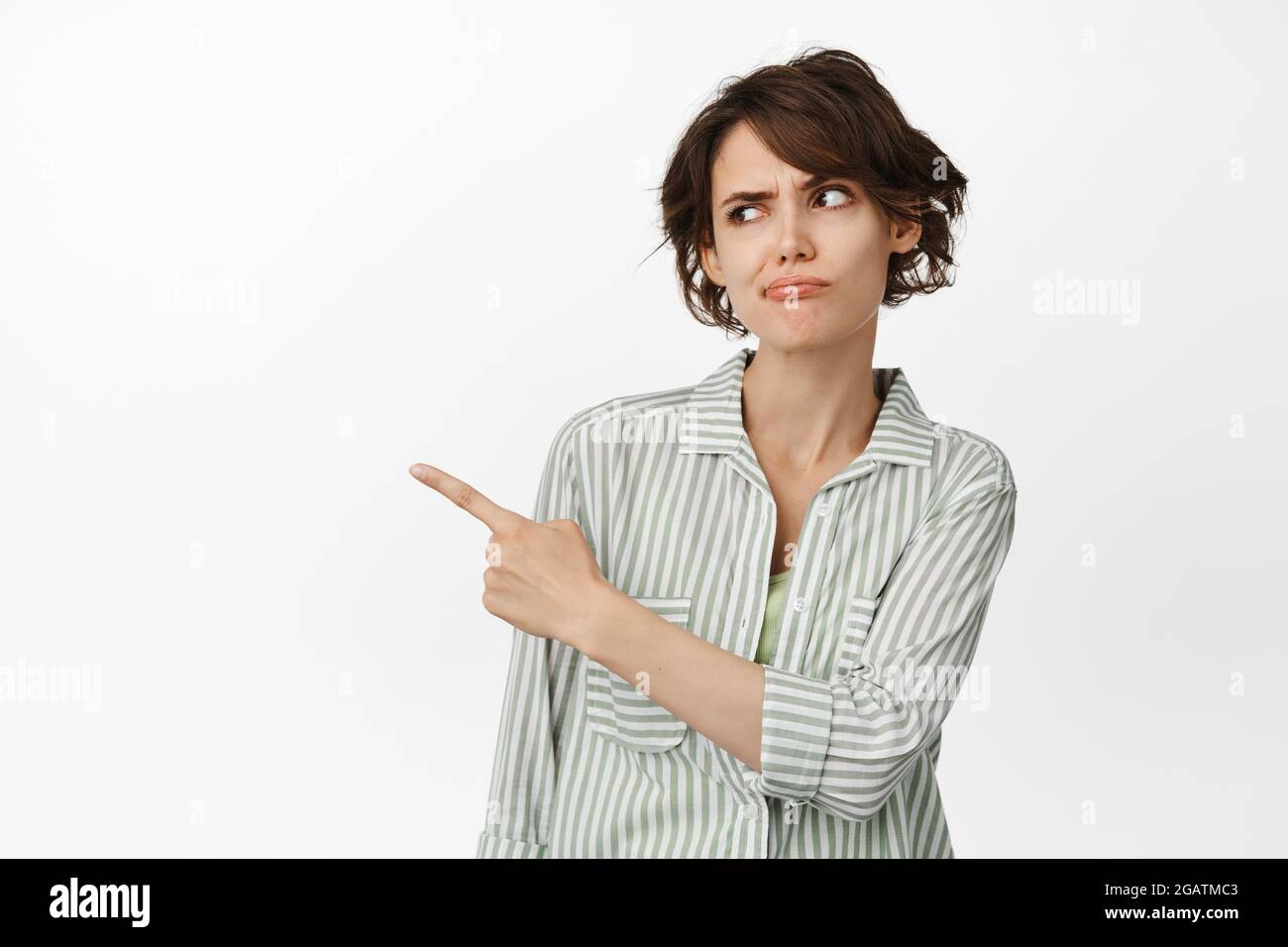 Skeptical, suspicious young woman pointing and looking left with raised ...