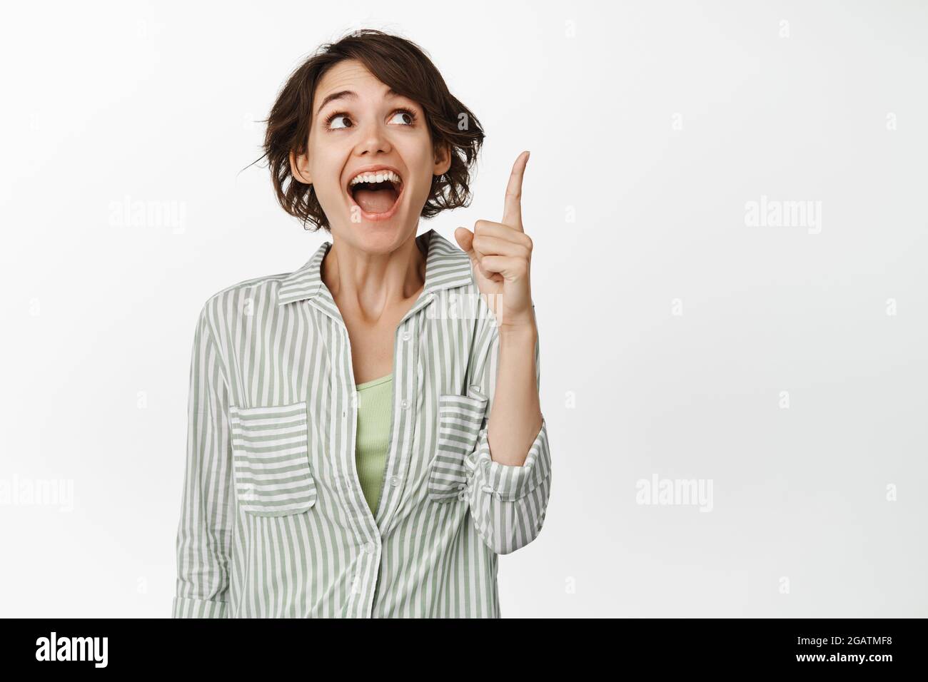 Excited brunette girl laughing, smiling and pointing finger up, chuckle ...