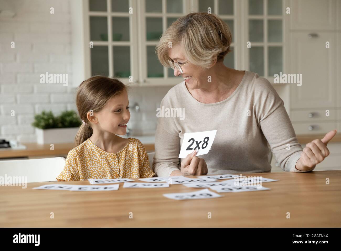 Smiling mature grandmother with little granddaughter learning ...