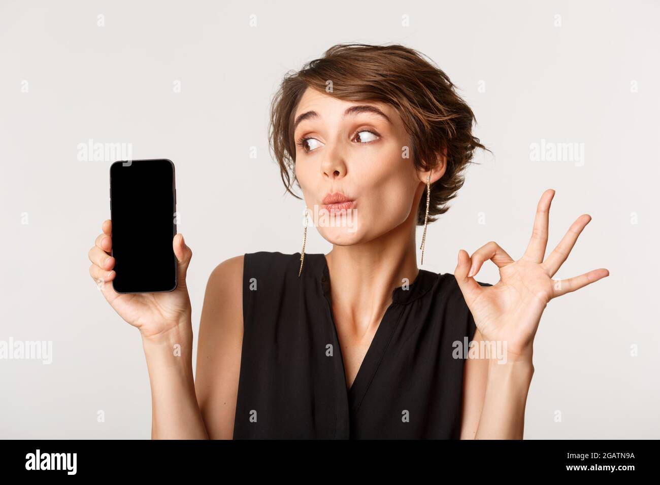 Close-up of silly pretty woman pouting, showing mobile phone screen and ...