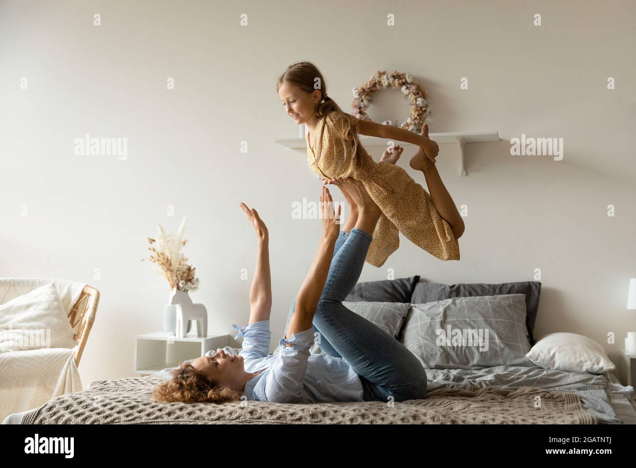 Strong mother lifting adorable little daughter on legs, having fun ...