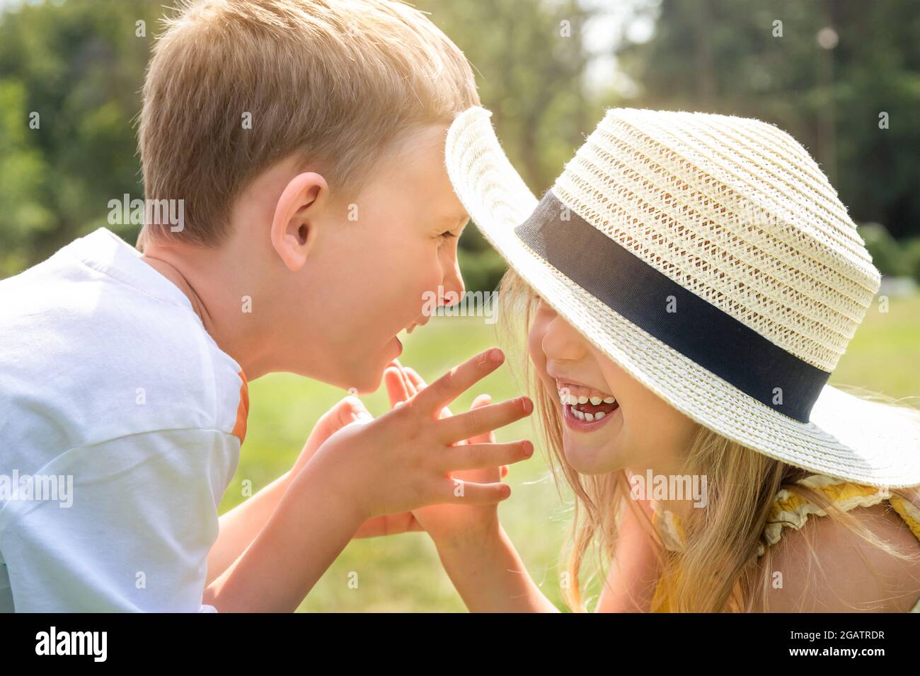 Boy and girl playing outdoors on a summer day, laughing and holding ...