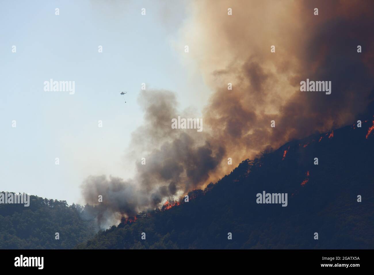 A helicopter flies through smoke rising from a forest fire in Marmaris ...