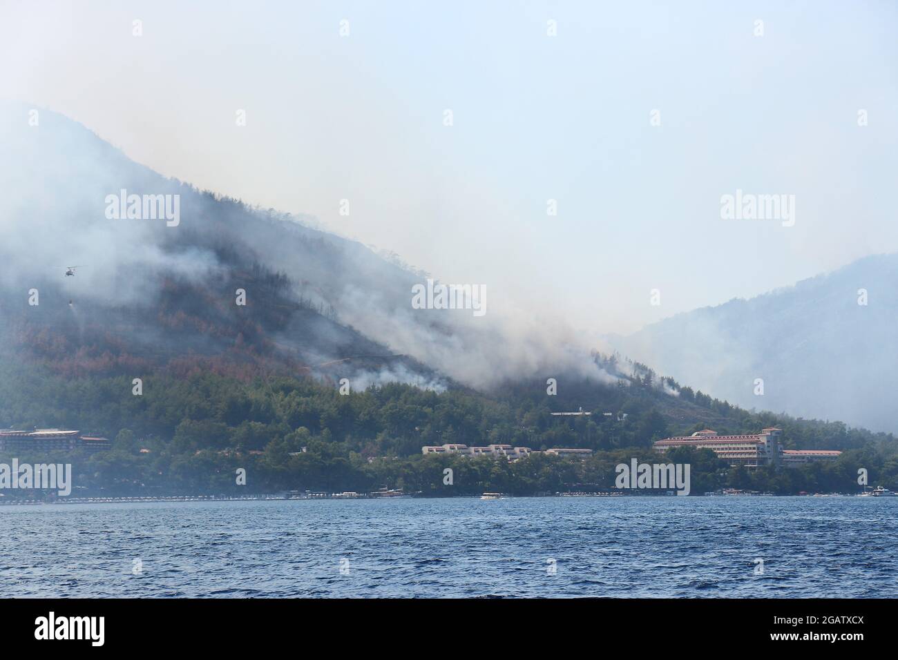 A helicopter flies through smoke rising from a forest fire in Marmaris ...