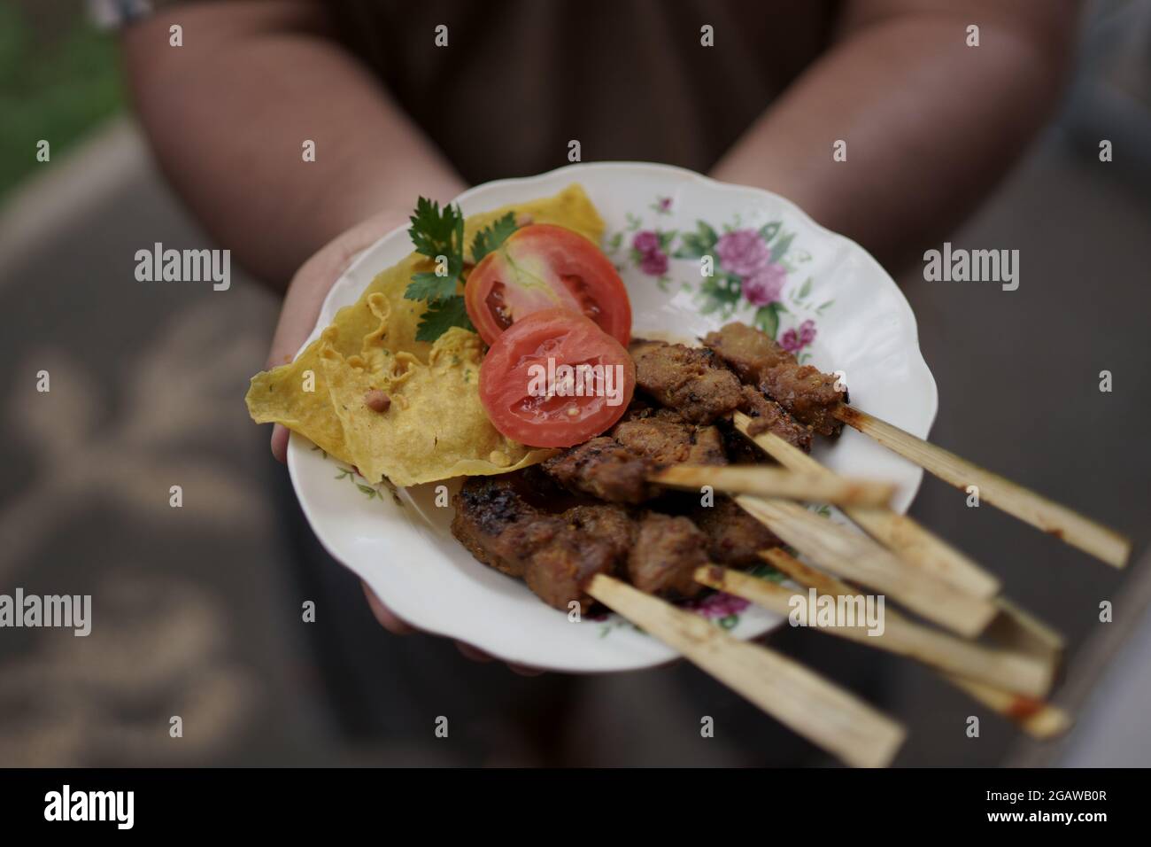 a serving of Balinese fish satay topped with fresh tomatoes, celery and ...