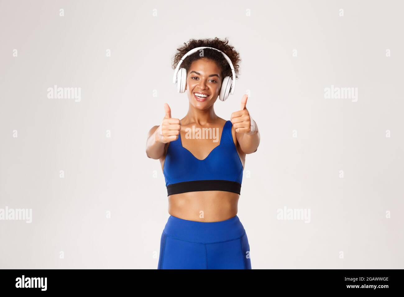 Happy african-american female athelte in blue sportswear, listening ...