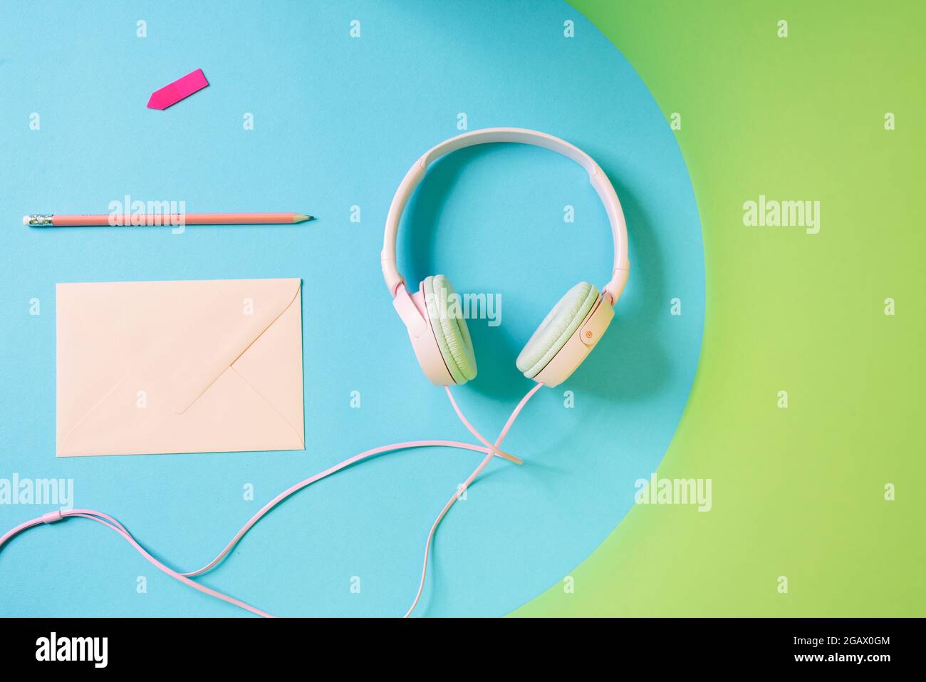 Overhead view of a set of wired headphones, writing and a pencil lying ...
