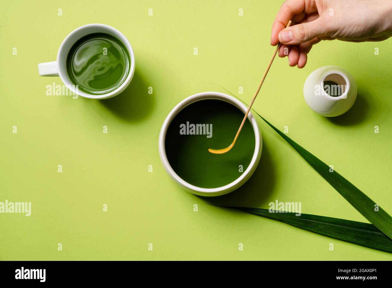 Overhead of a woman's hand mixing with a matcha spoon in a bowl ...