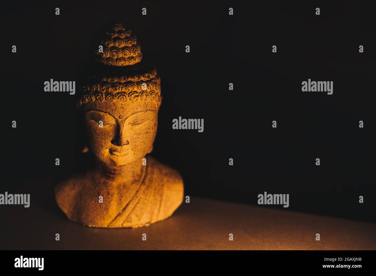 Buddha statue resting on table with black background Stock Photo - Alamy