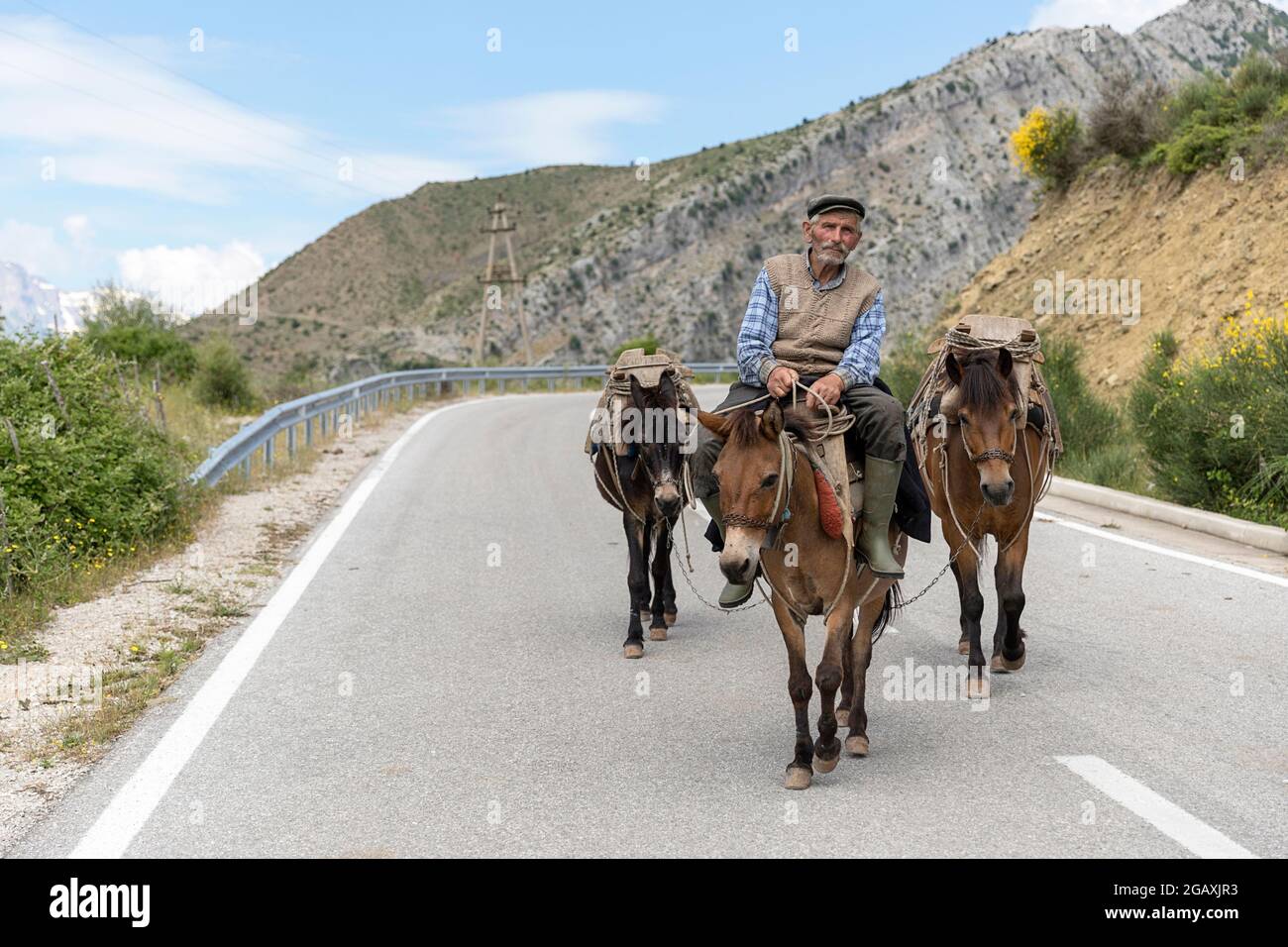 Local men riding a donkey on the road in the mountains of the southern ...