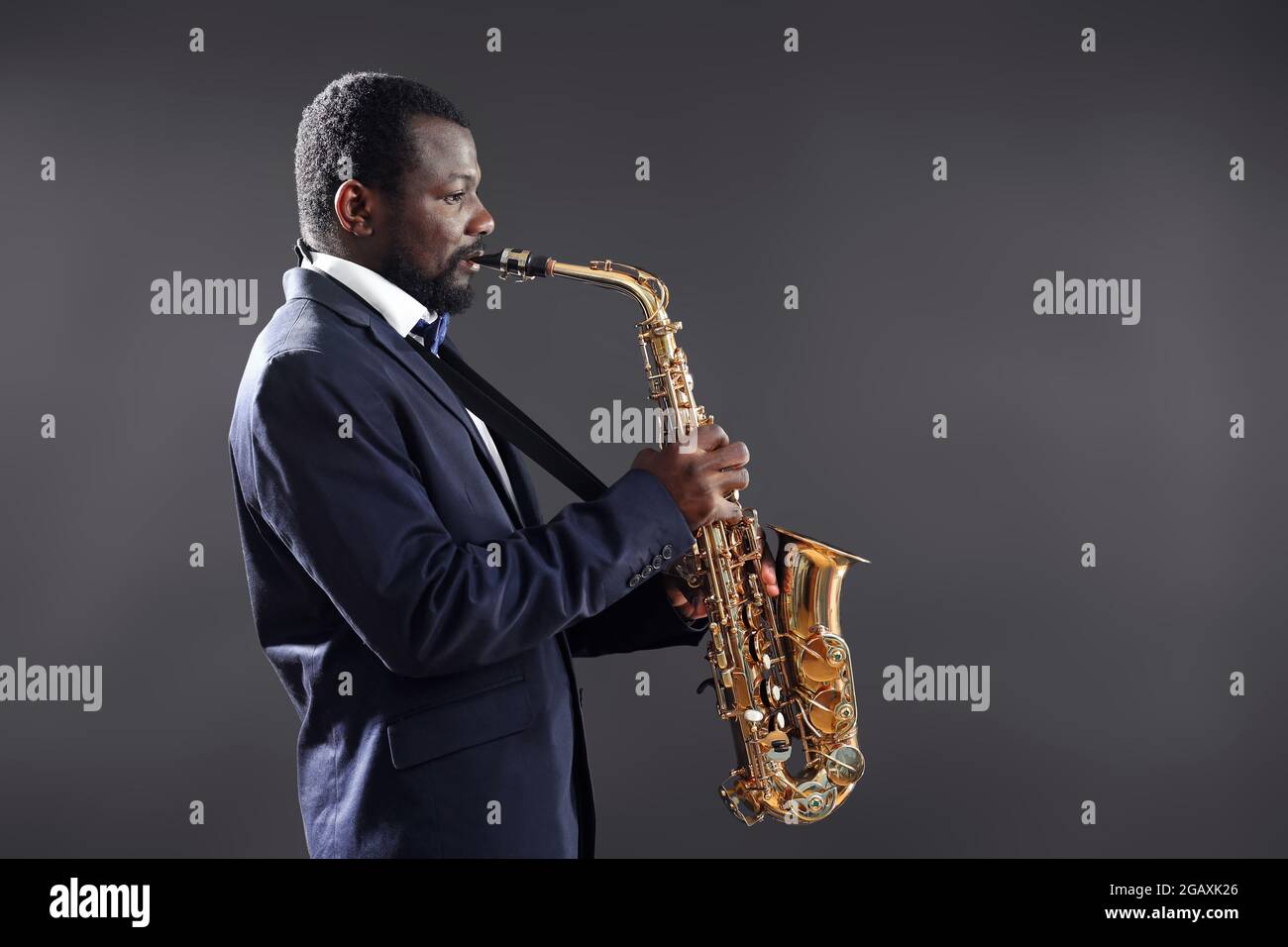 African American jazz musician playing the saxophone on grey background ...