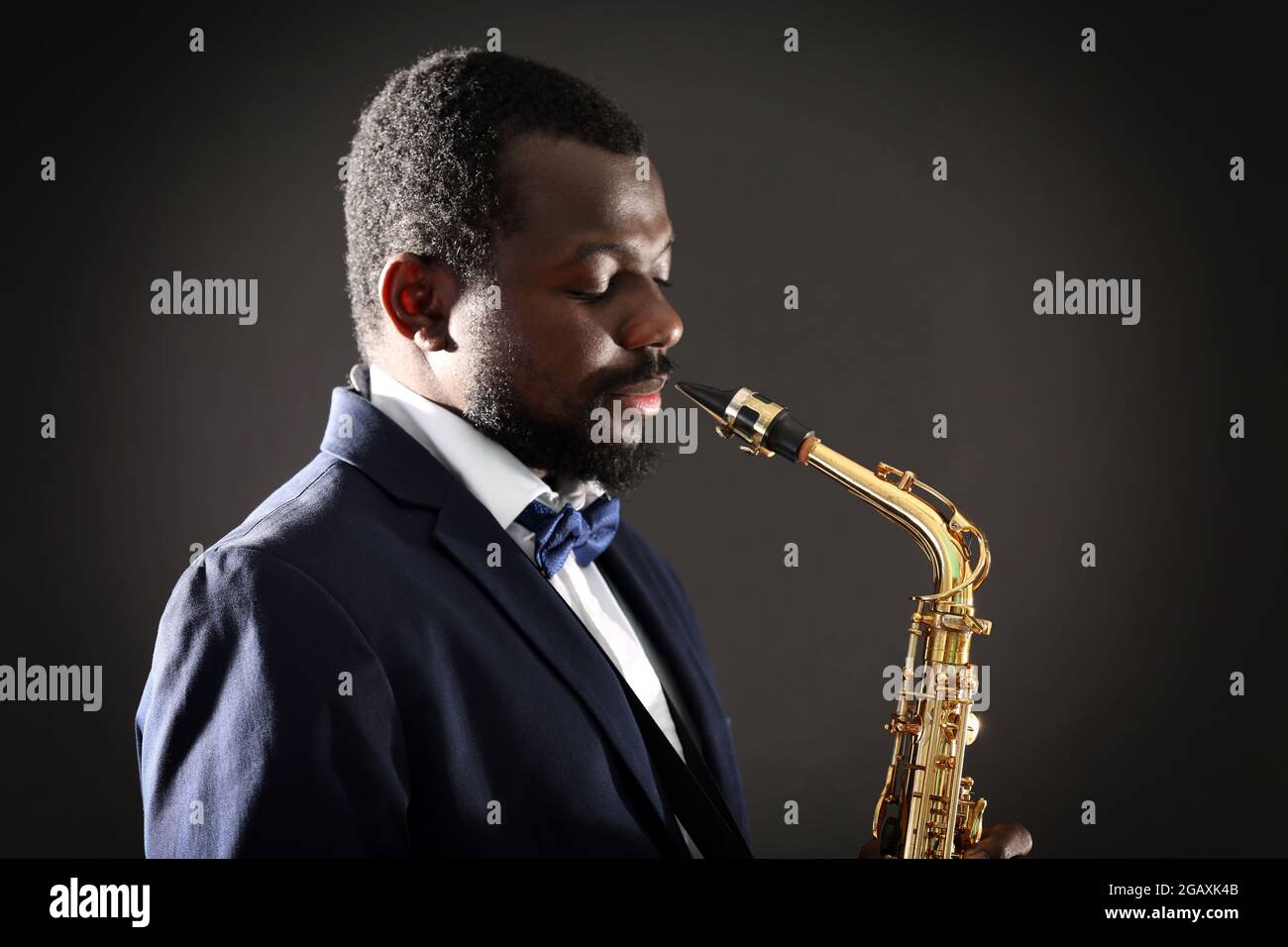 African American jazz musician playing the saxophone on grey background ...