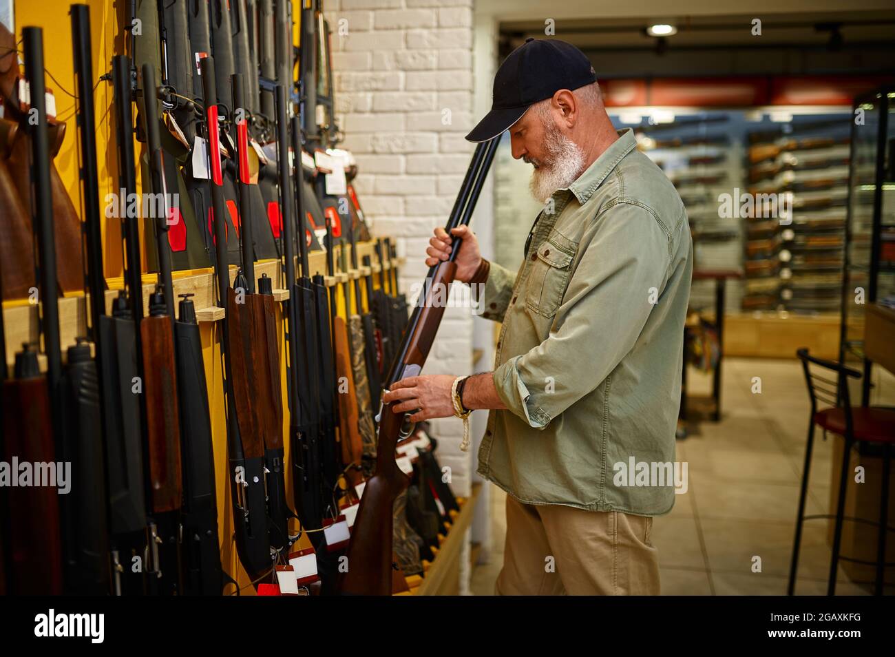 Hunter at showcase with hunting rifles, gun store Stock Photo - Alamy