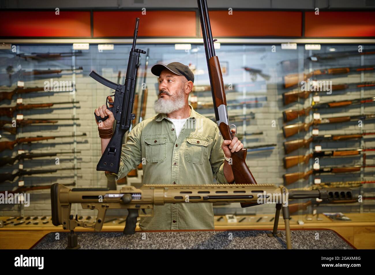 Happy male hunter with two rifles in gun store Stock Photo - Alamy