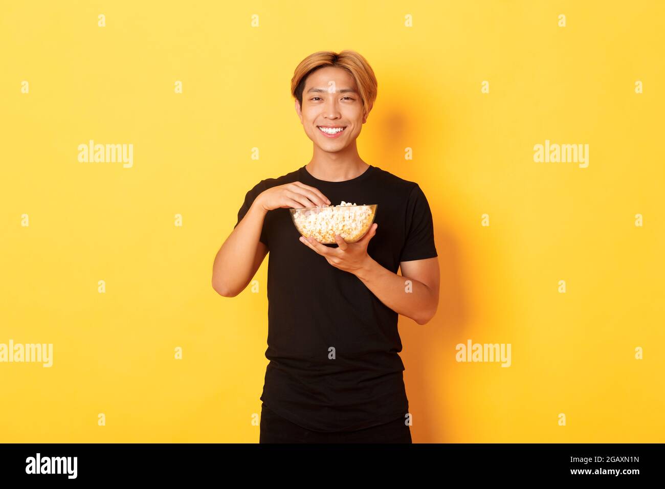 Pleased handsome korean guy smiling happy as enjoying watching movie or ...