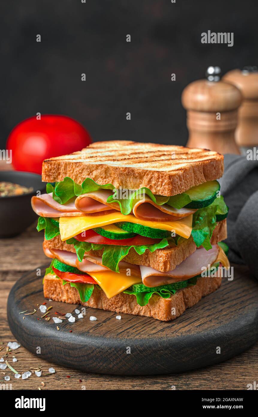 Double sandwich with cheese, ham and fresh vegetables on a brown ...
