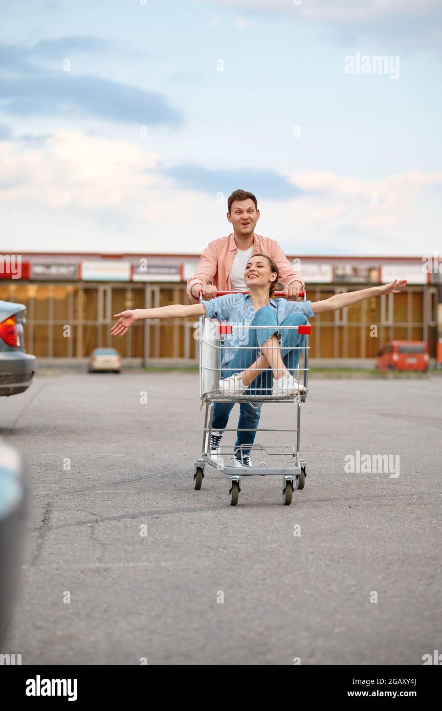 Funny family couple rides in cart on parking Stock Photo - Alamy