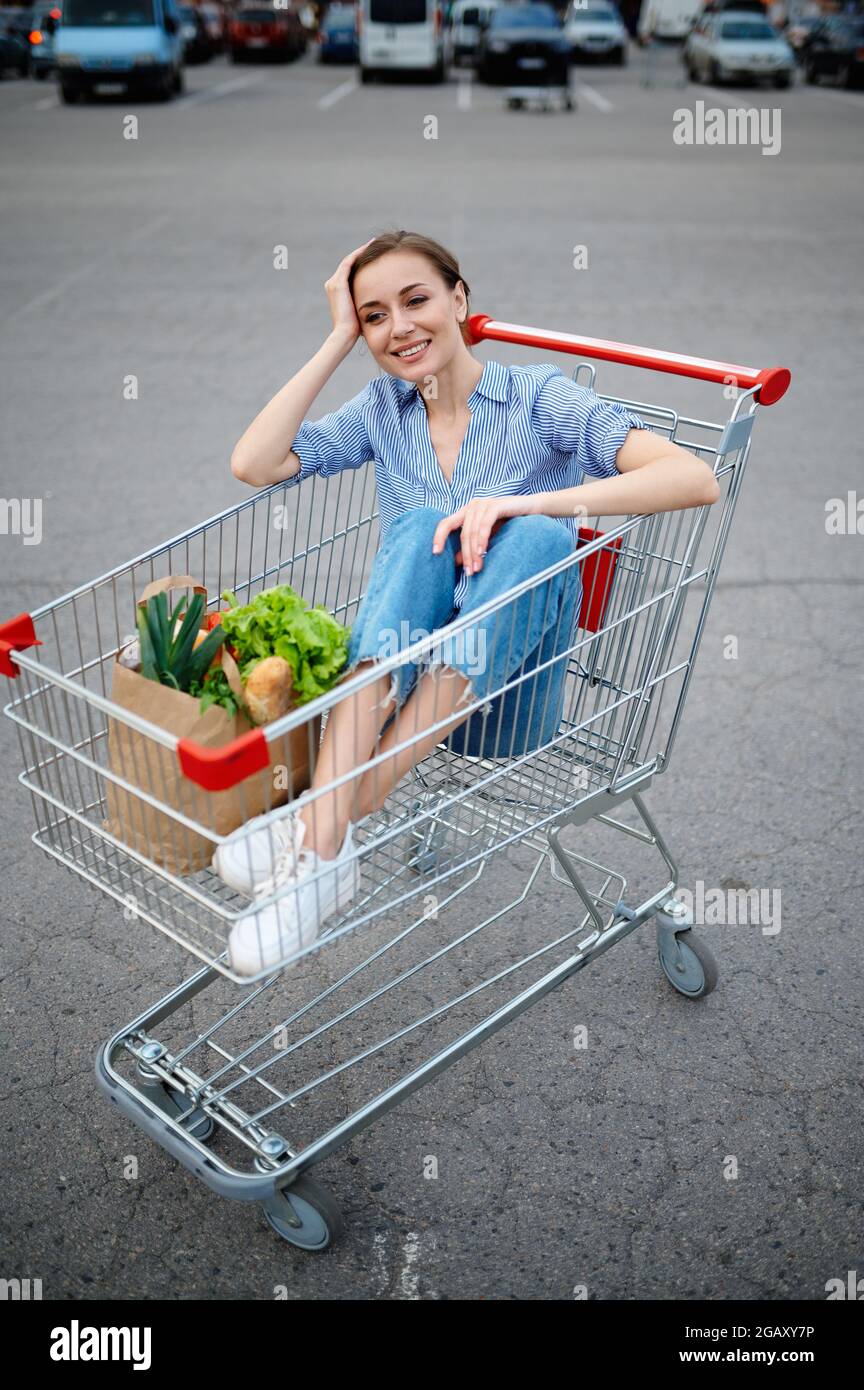 Funny woman sitting in cart on supermarket parking Stock Photo - Alamy