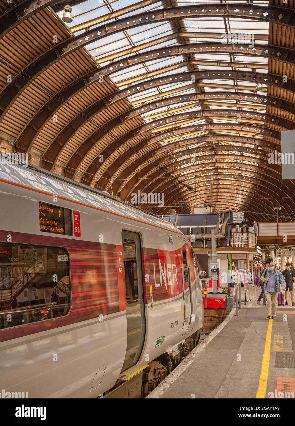 A sleek modern locomotive stands at railway station platform and a19th ...
