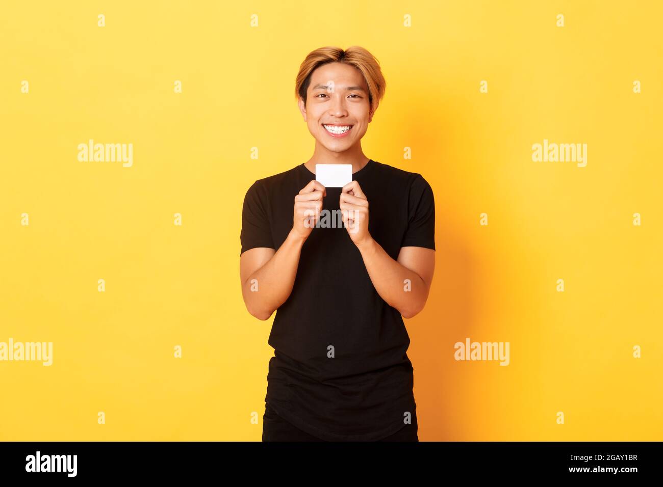 Excited happy asian guy smiling and showing credit card, standing ...