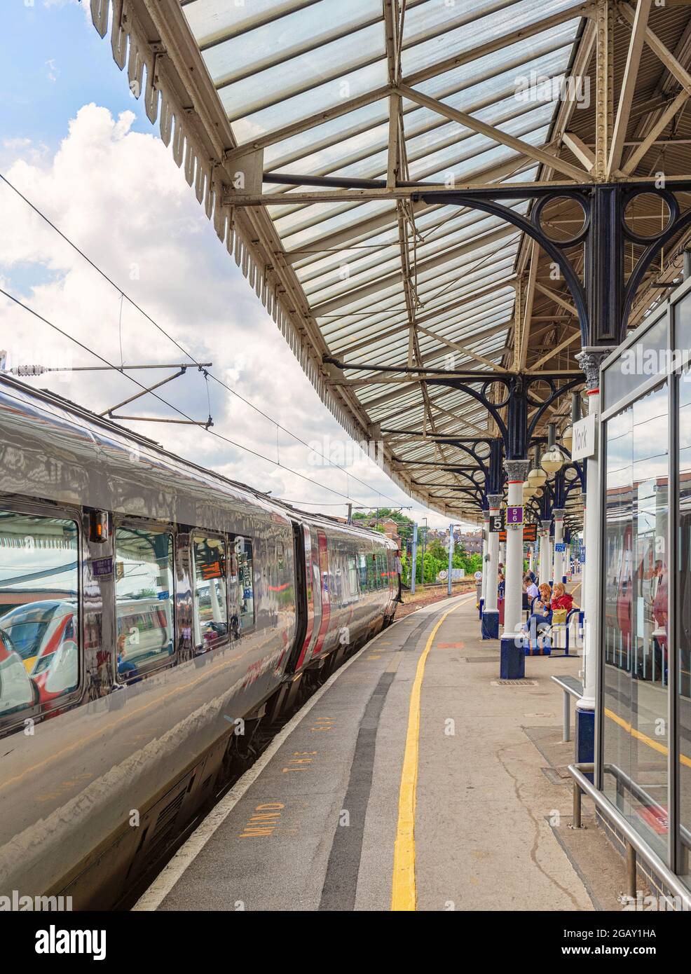 A sleek modern locomotive stands at railway station platform and a 19th ...