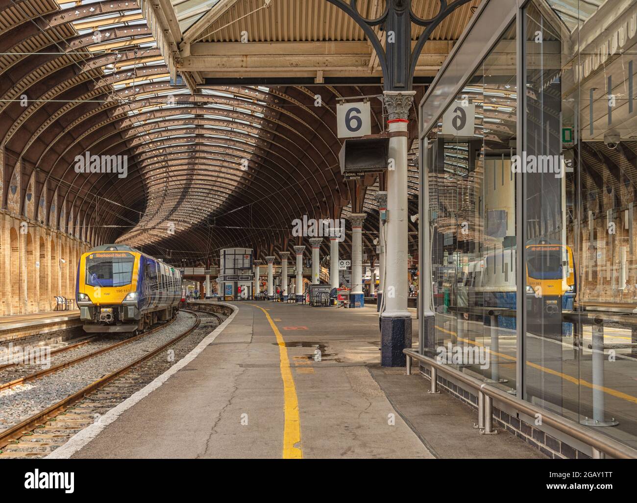 View of a railway station platform with a waiting train and its mirror ...