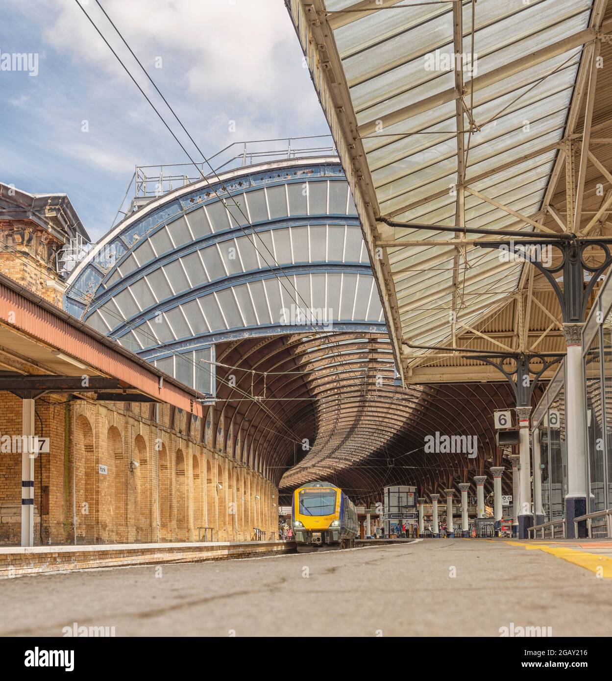 A low-angle view of a railway station with a train waiting to depart. A ...