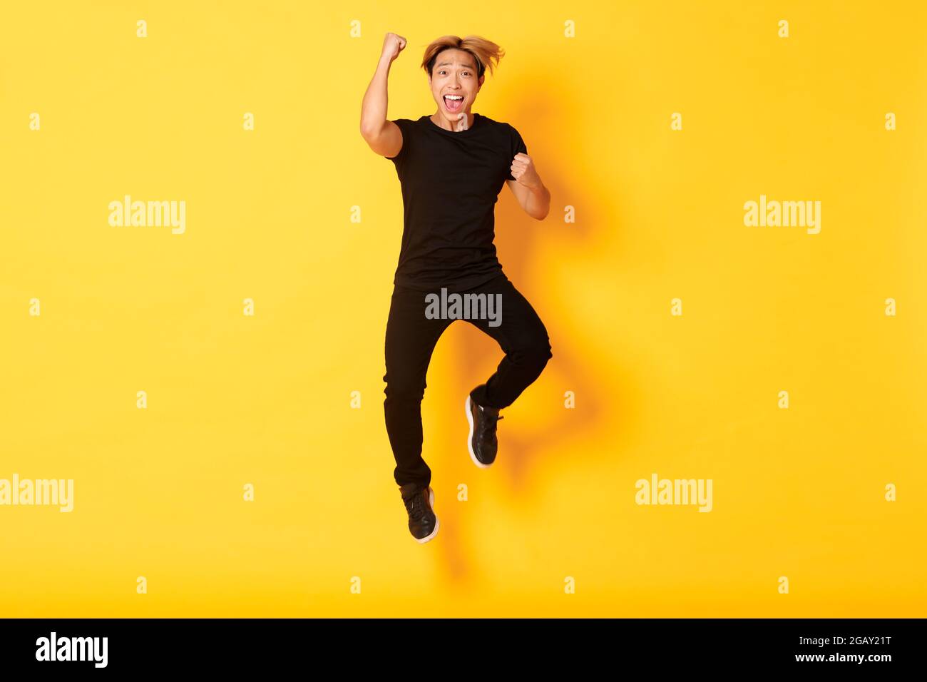Full-length of happy attractive asian guy in black clothes jumping and ...