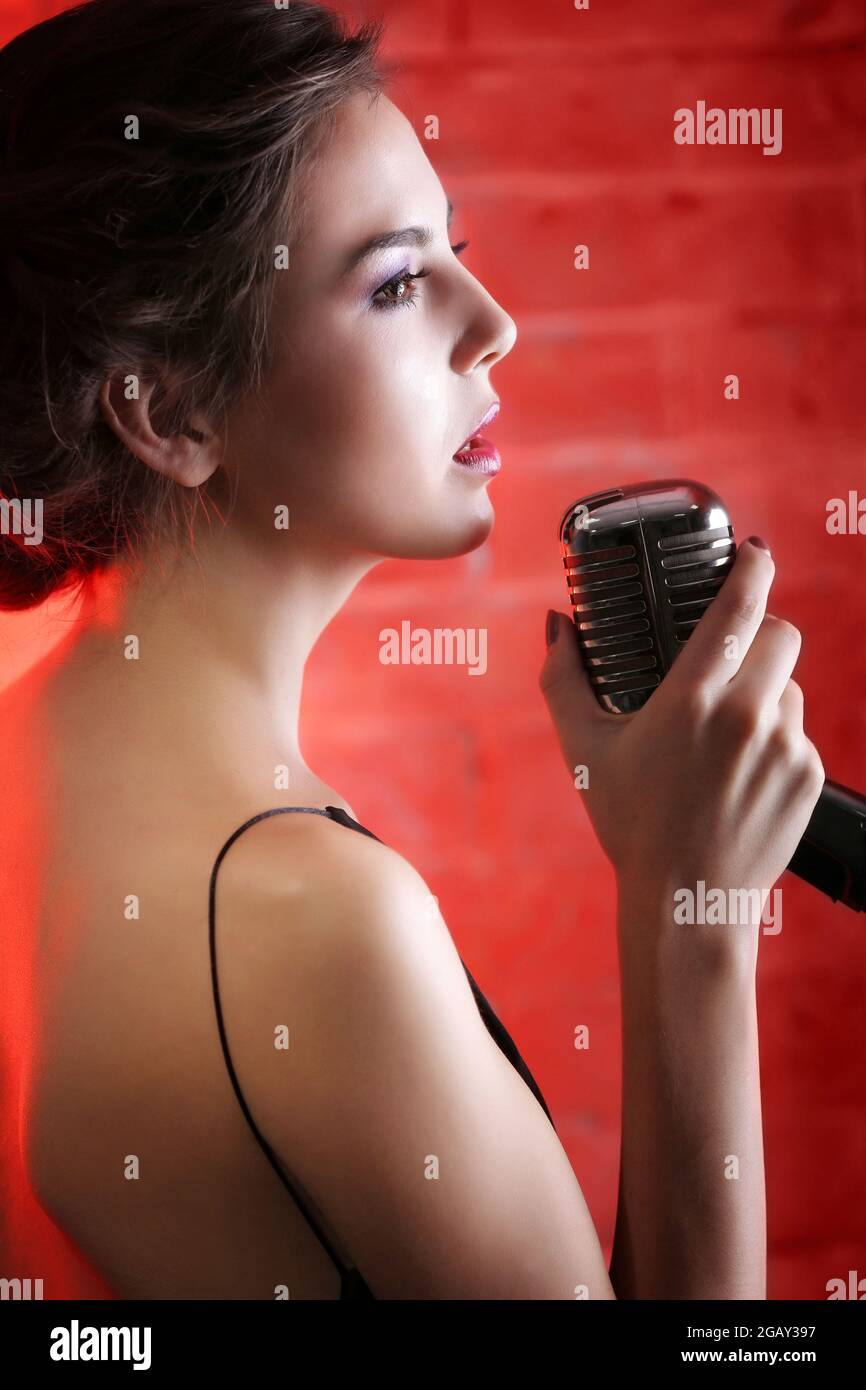 Beautiful brunette singing woman on brick wall background, backside ...